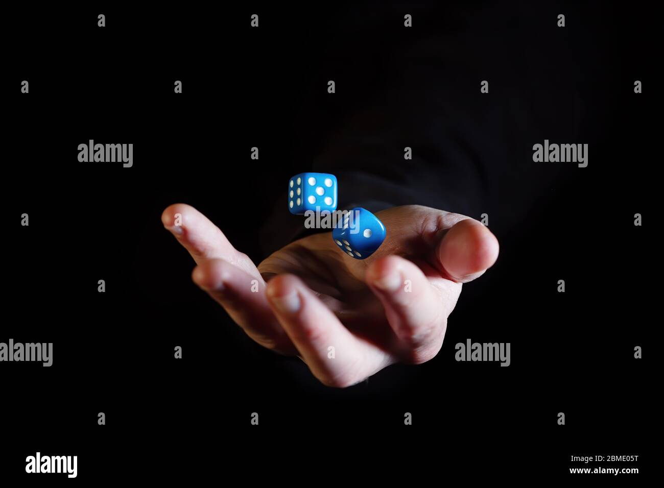 Hand throwing dice cubes in the air against black background Stock ...
