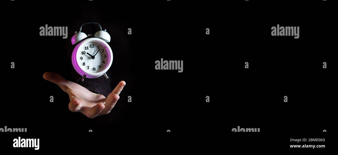 White alarm clock with purple highlights hovering above male hand ...