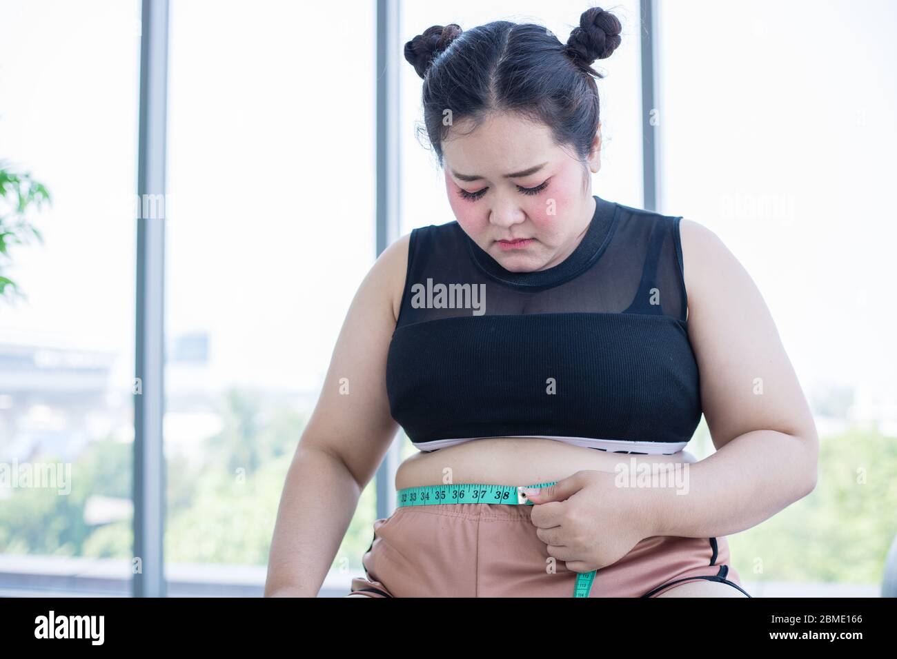 Asian overweight woman measuring fat layer with waistline at home Stock ...