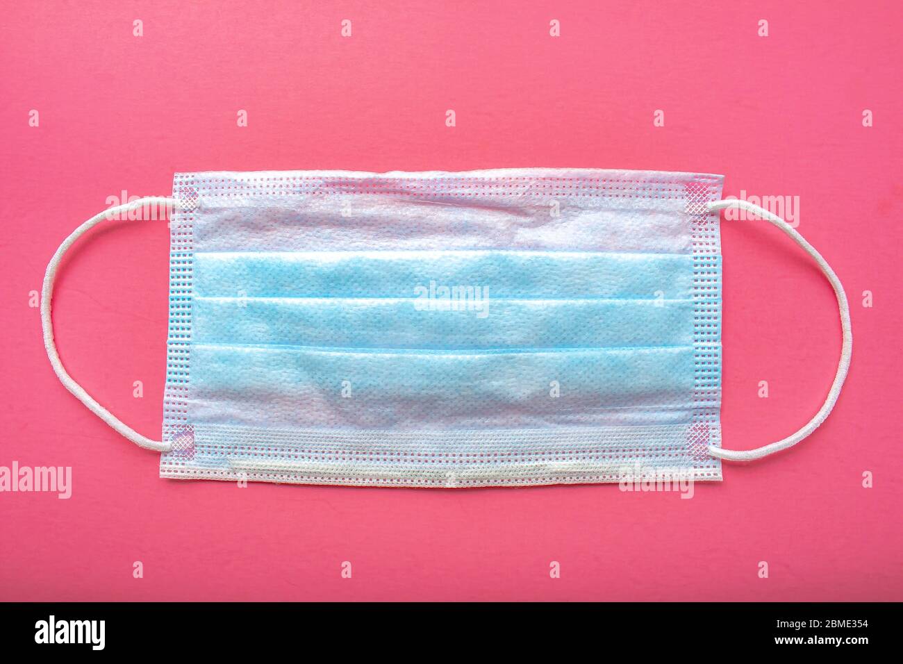 A medical surgical face mask on a pink background Stock Photo - Alamy