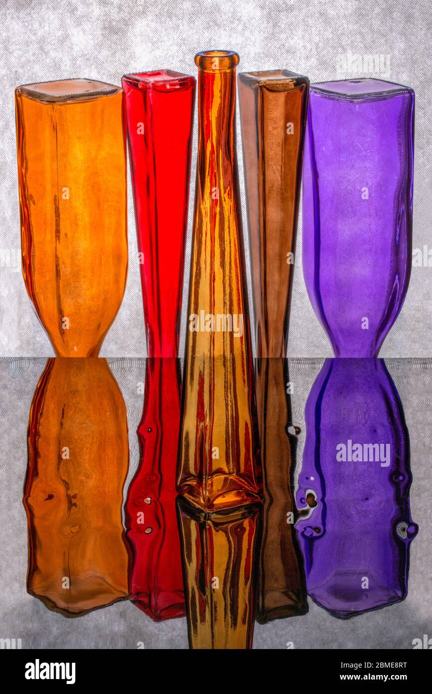 Still life with inverted colored bottles on a reflective surface Stock ...