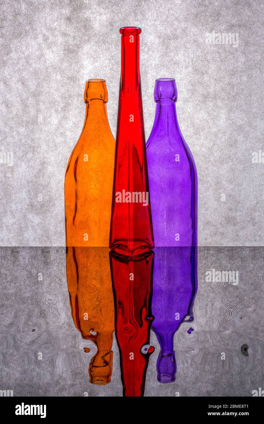 Still life with inverted colored bottles on a reflective surface Stock ...