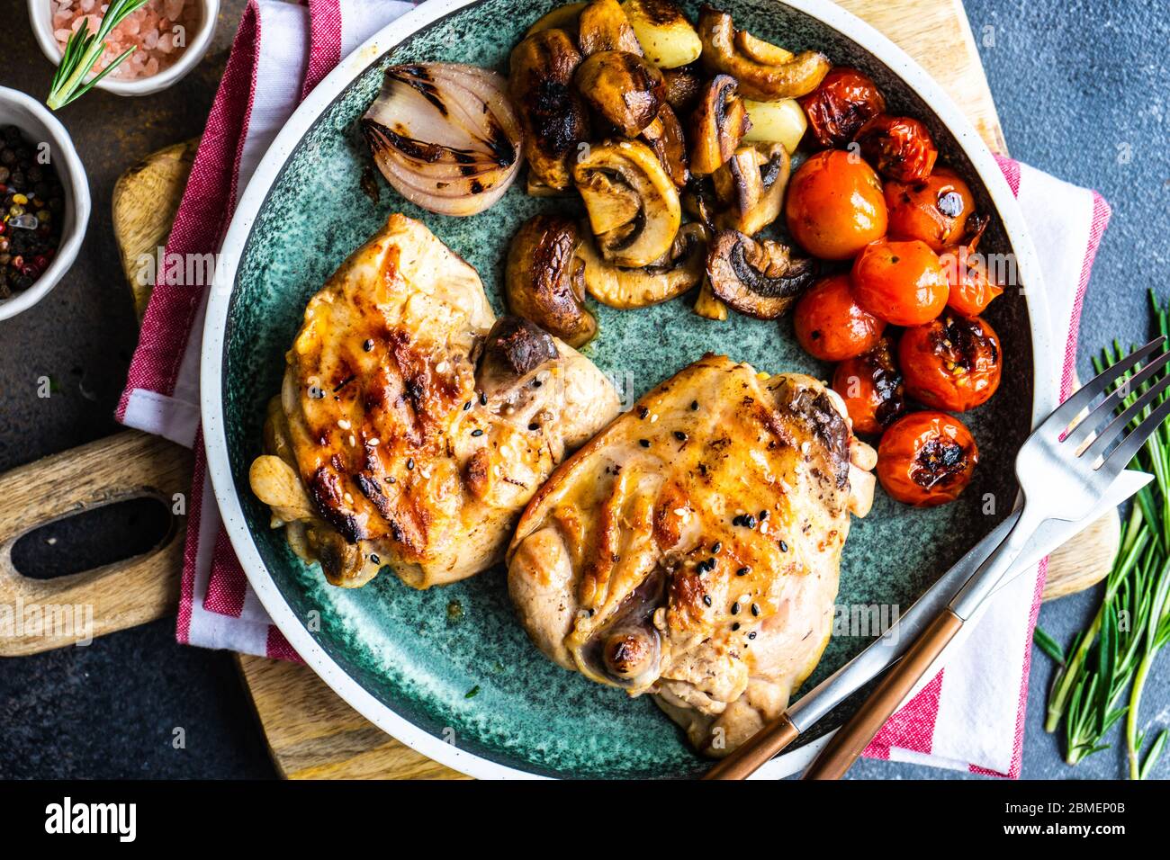 Grilled chicken meat and vegetables served on plate and spices on stone ...