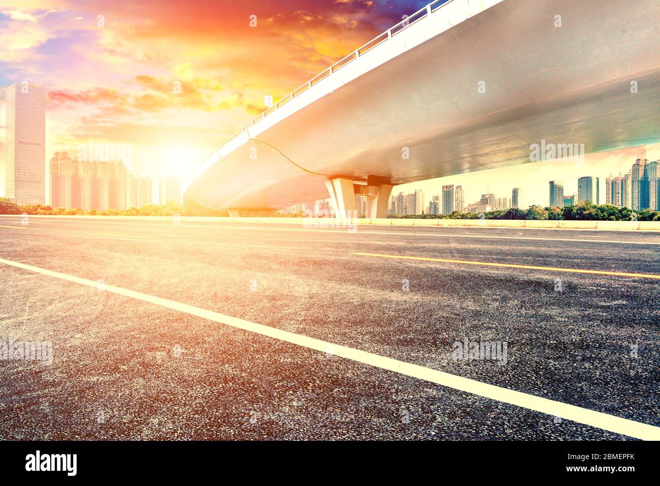 Under the overpass, car-free asphalt road, modern city building skyline ...