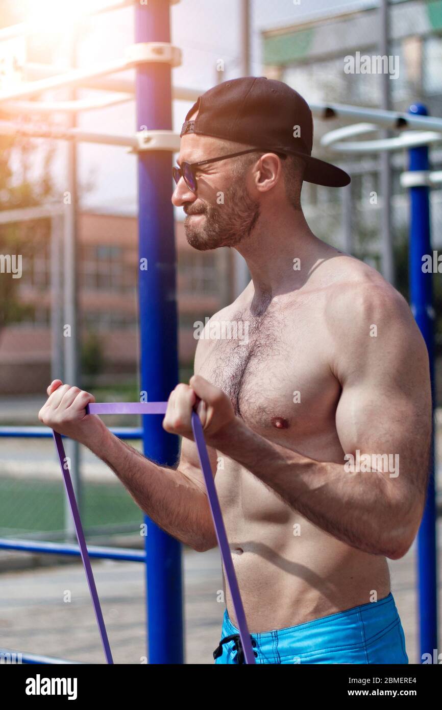 strong young man making exercises with rubber outdoor Stock Photo - Alamy