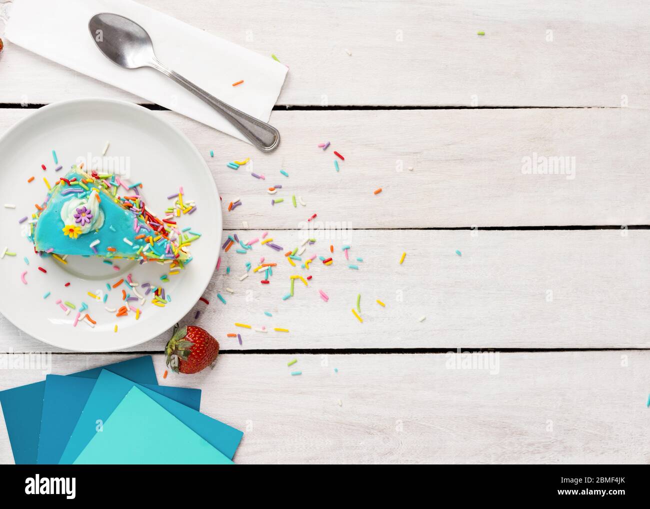 A slice of colorful sponge cake with confetti sprinkles a spoon and ...