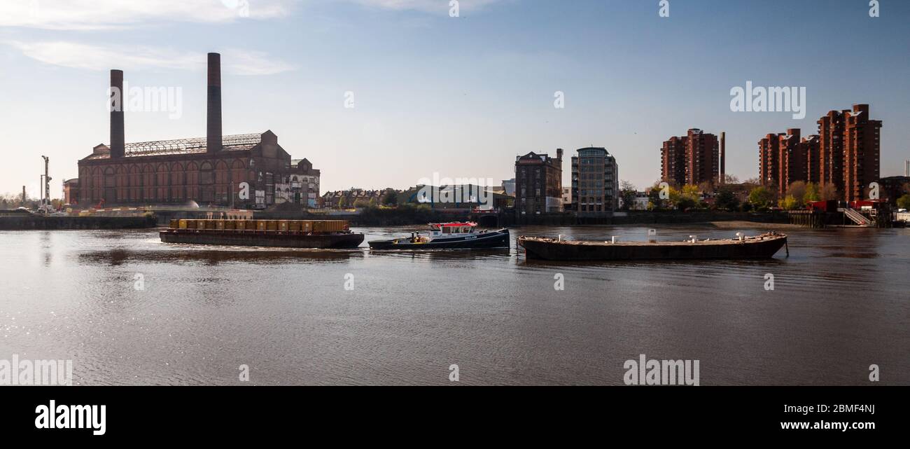 A tug tows a barge of containerised waste down the Thames past Lots ...