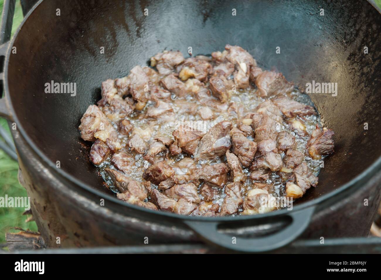 Pilaf Cooking in cauldron on fire outdoors series. Pieces of lamb meat ...