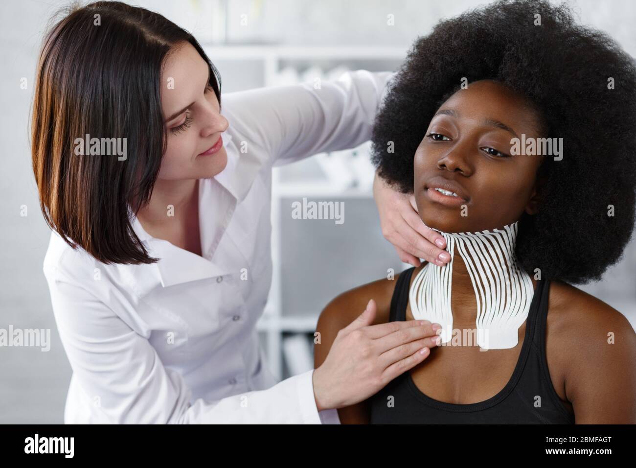 Kinesiology taping. Physiotherapist applying kinesiology tape to patient neck. Therapist ...