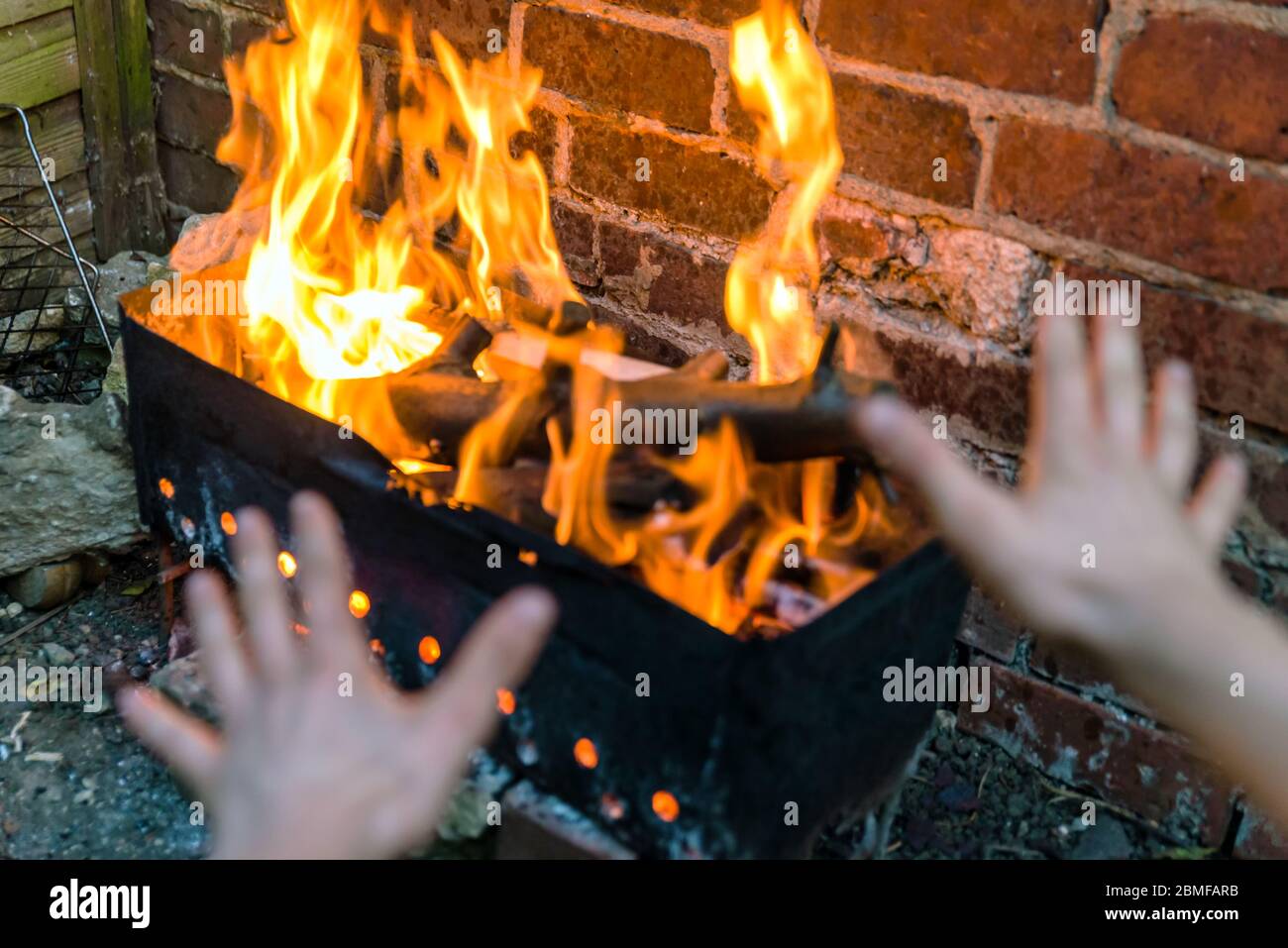 kids warming their arms over fire and grill on red brick wall ...