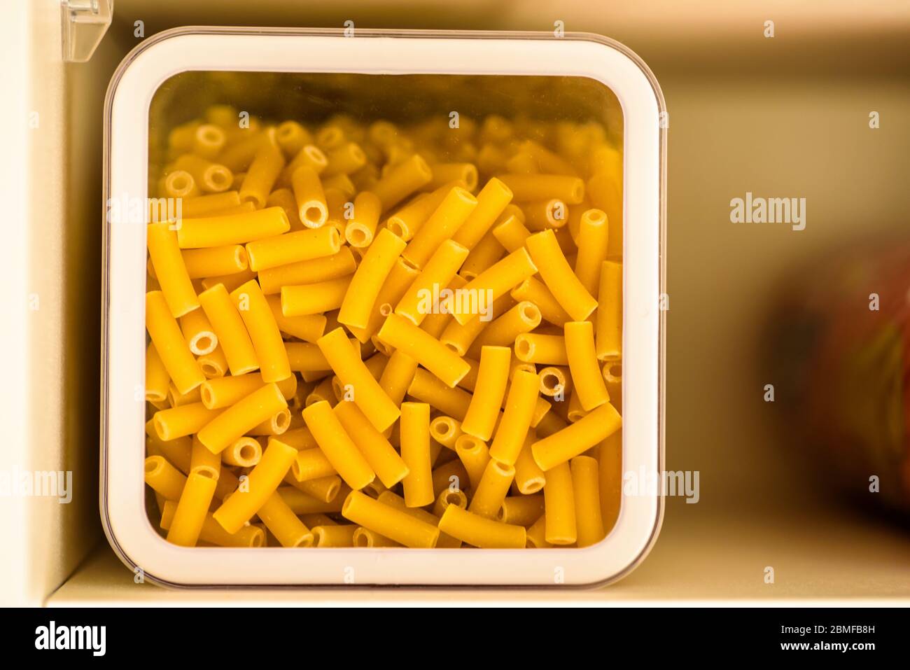 raw italian macaroni pasta inside clear storage container in kitchen ...