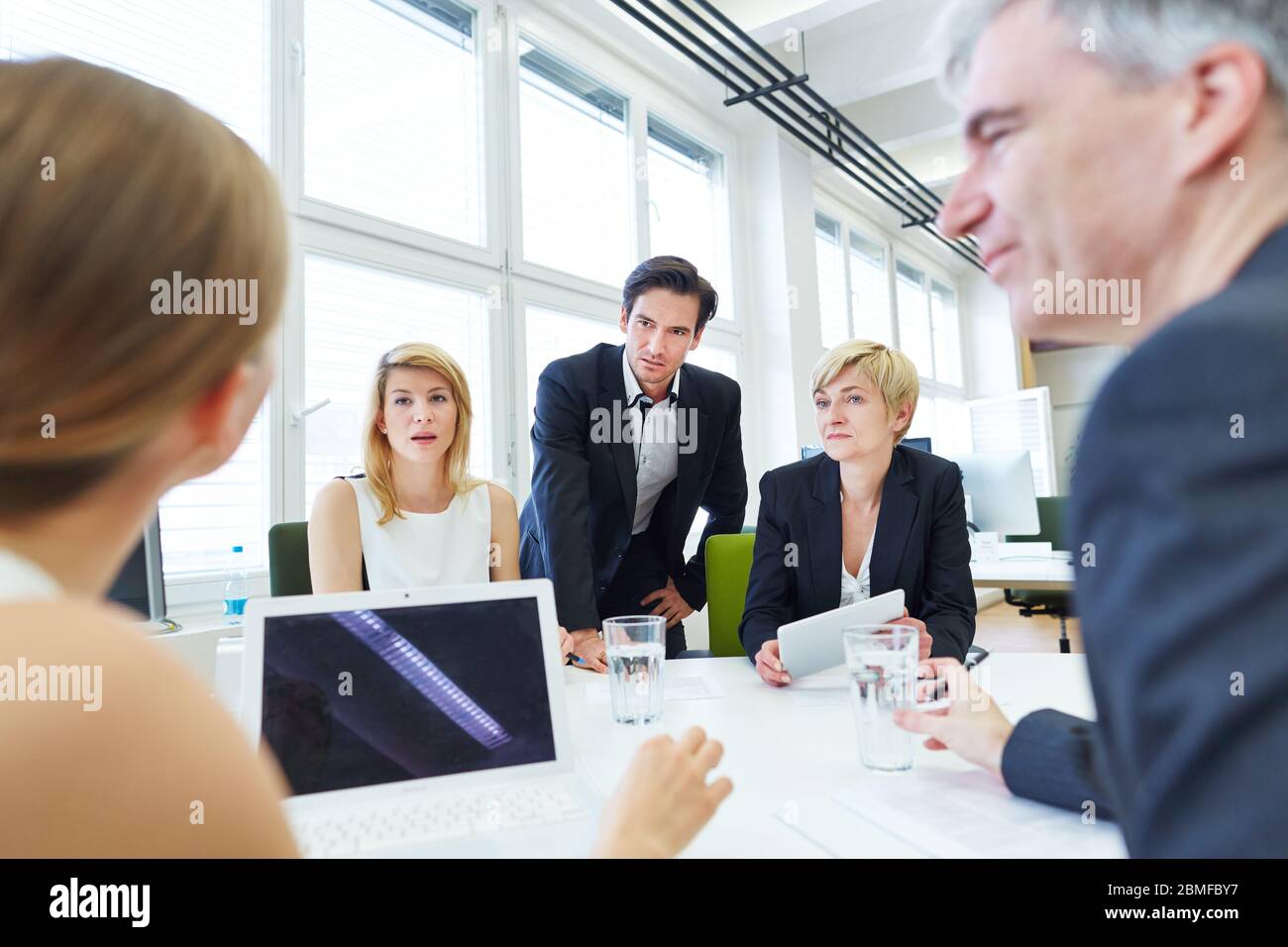 Business people sit around a table in a meeting Stock Photo - Alamy