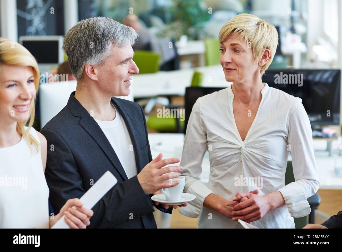 Two older businesspeople talk to each other in the office in a friendly ...