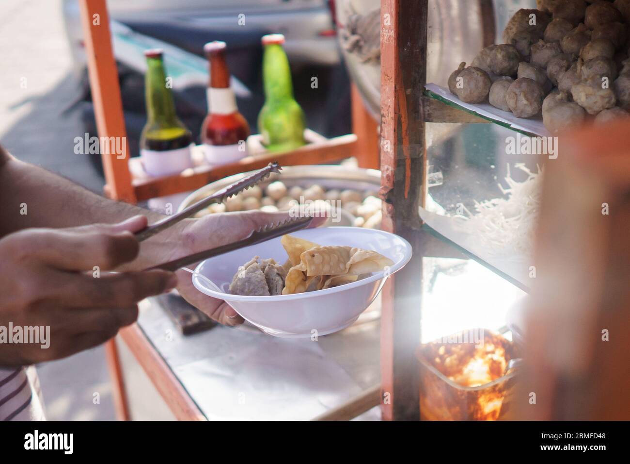 indonesian meatball street food vendor preparing the dish using tongs ...