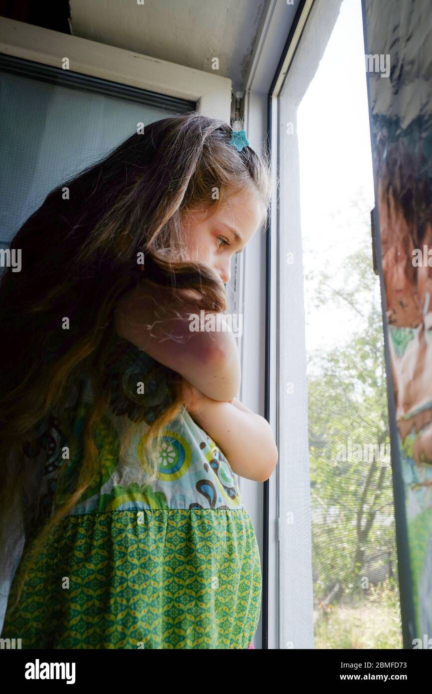 Little girl by the window. A 5 year old girl sits by the window at home ...