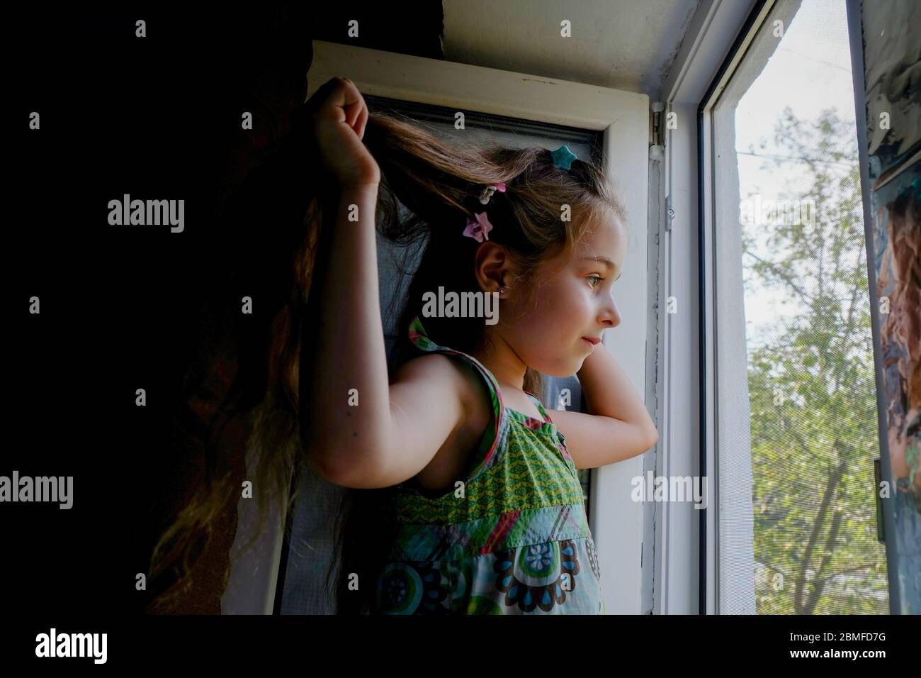 Little girl by the window. A 5 year old girl sits by the window at home ...