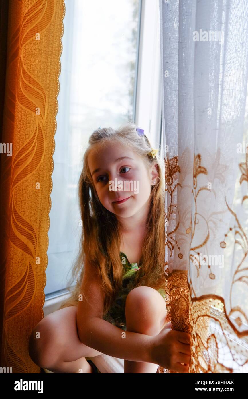Little girl by the window. A 5 year old girl sits by the window at home ...
