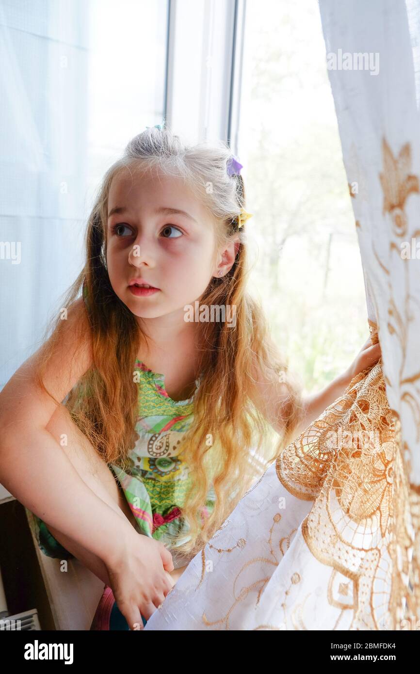 Little girl by the window. A 5 year old girl sits by the window at home ...