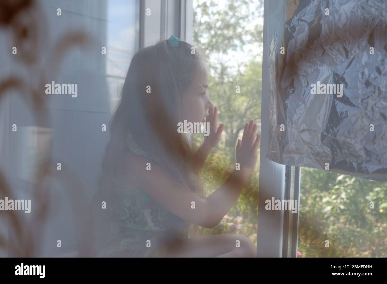 Little girl by the window. A 5 year old girl sits by the window at home ...