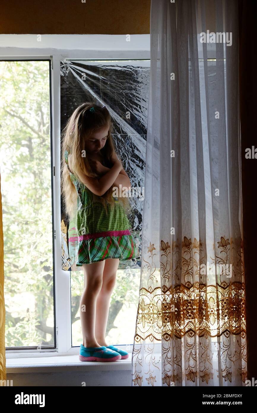 Little girl by the window. A 5 year old girl sits by the window at home ...
