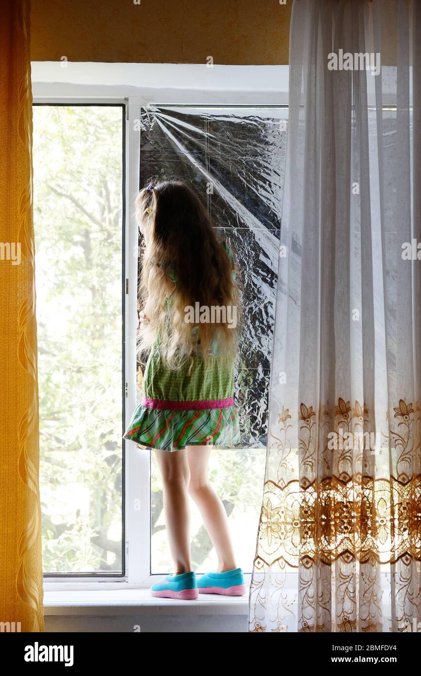 Little girl by the window. A 5 year old girl sits by the window at home ...