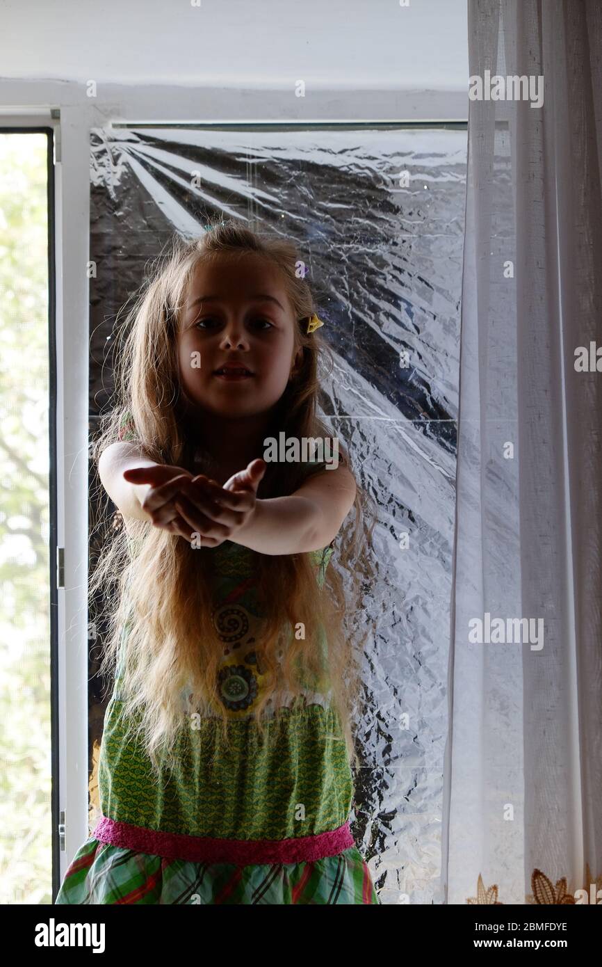 Little girl by the window. A 5 year old girl sits by the window at home ...