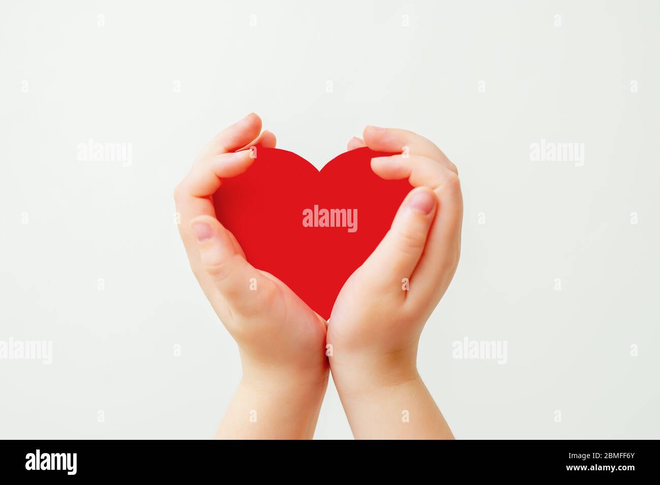 Paper red heart in hands of child on white background. Child love ...