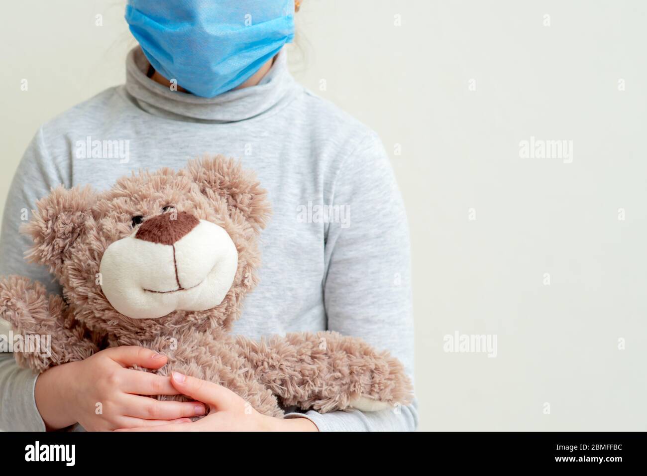 Child is holding Teddy bear wearing protective medical mask on white ...