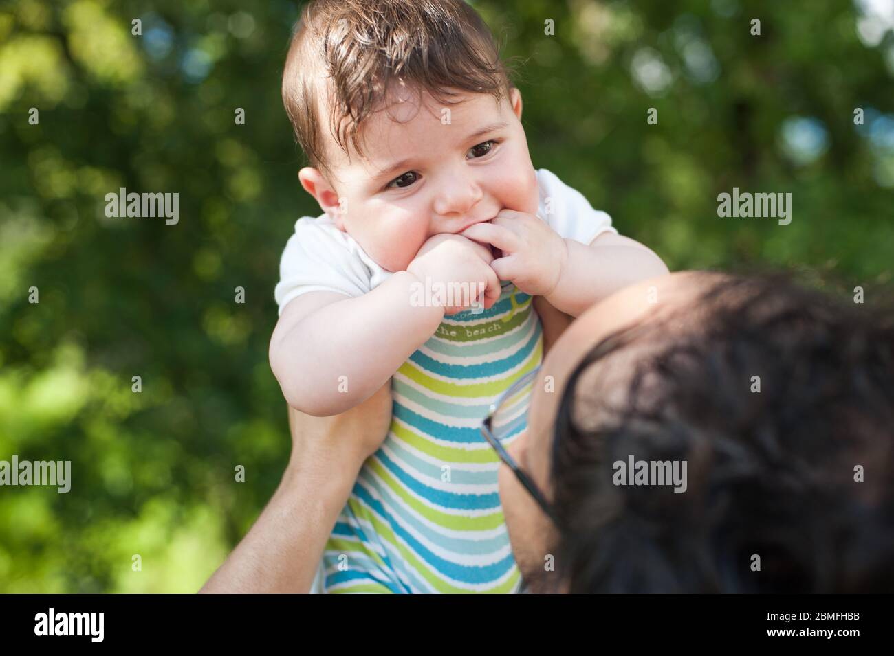front view of a cute baby boy in his father´s arms in nature Stock ...
