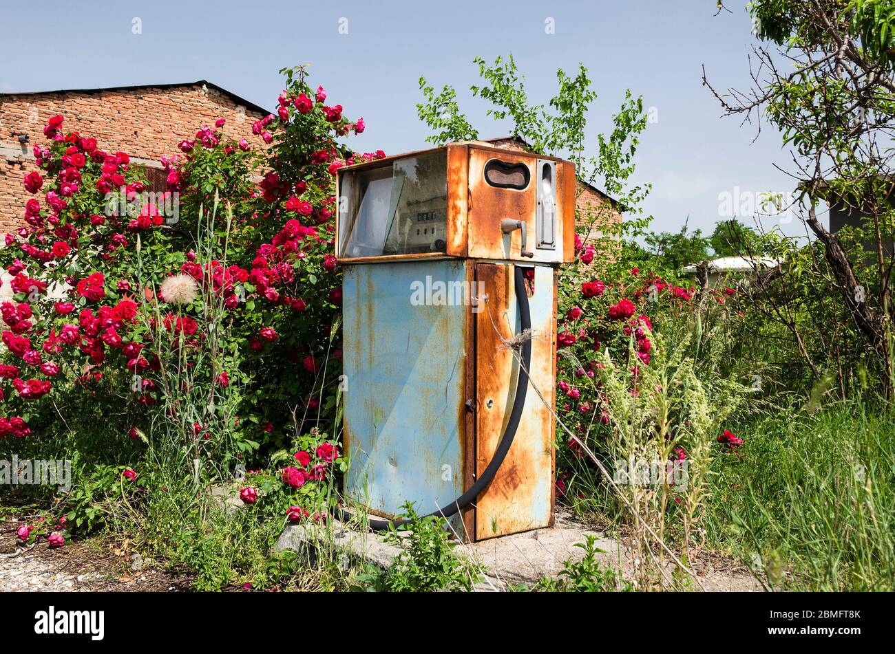A rusty old-fashioned gas pump in front of an abandoned gas station ...
