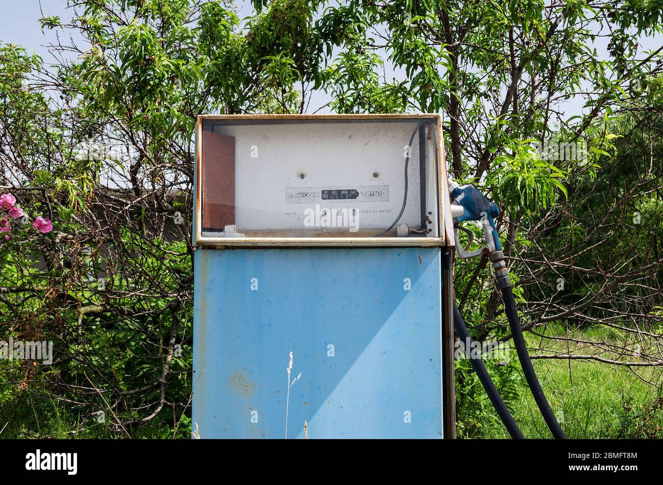 A rusty old-fashioned gas pump in front of an abandoned gas station ...