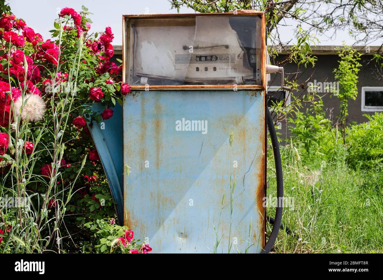 A rusty old-fashioned gas pump in front of an abandoned gas station ...