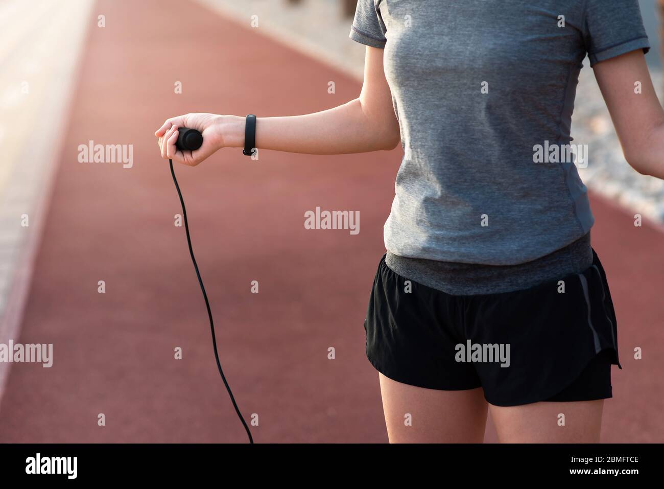 Woman holding a jumping rope on a running track before fitness training ...