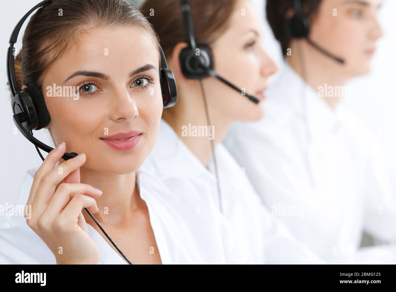 Call center. Beautiful young woman using headset and computer to help ...