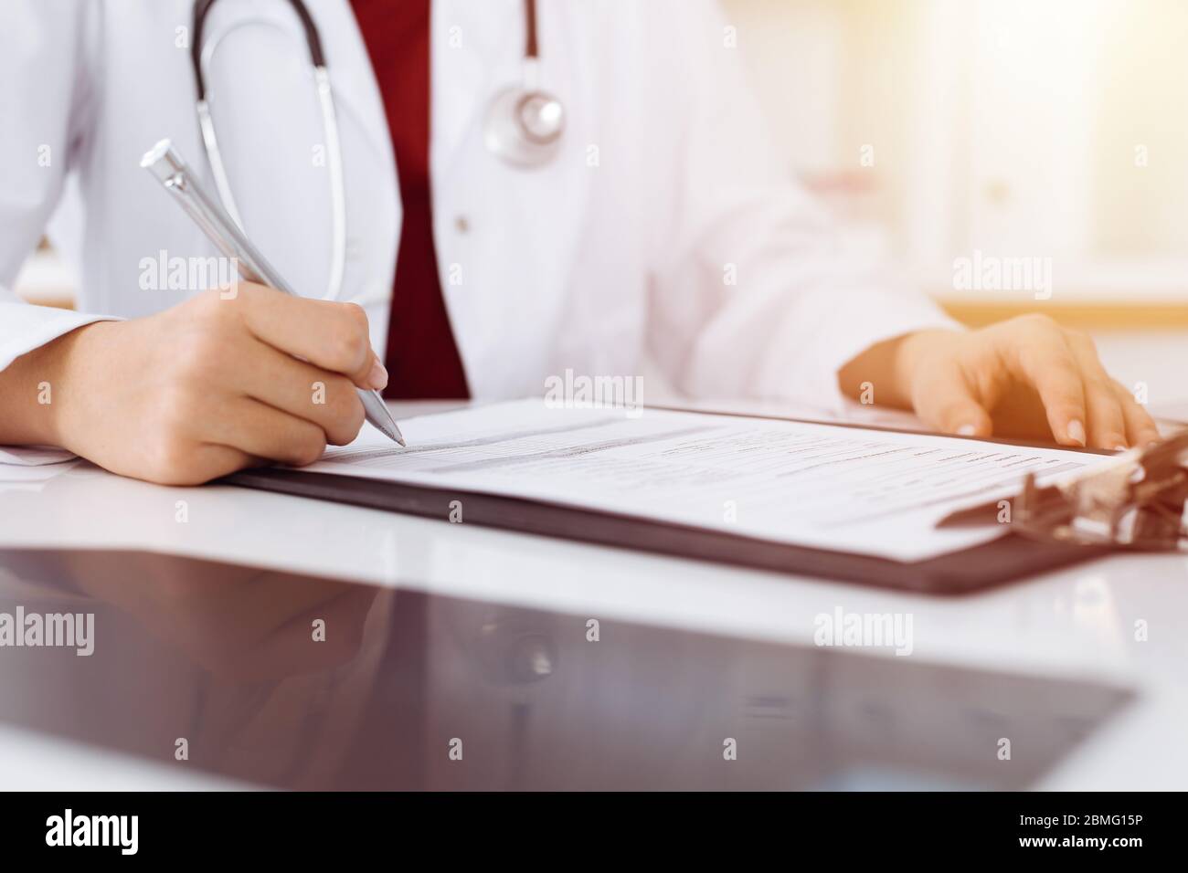 Unknown woman-doctor filling up an application form while consulting ...