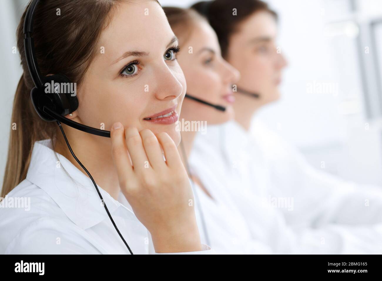Call center. Beautiful young woman using headset and computer to help ...