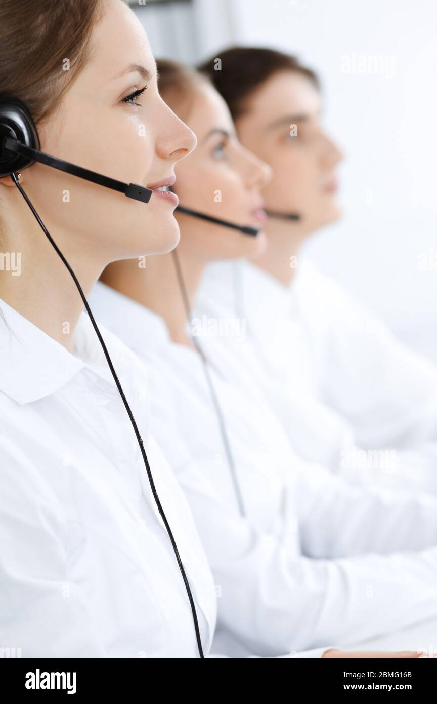 Call center. Beautiful young woman using headset and computer to help ...