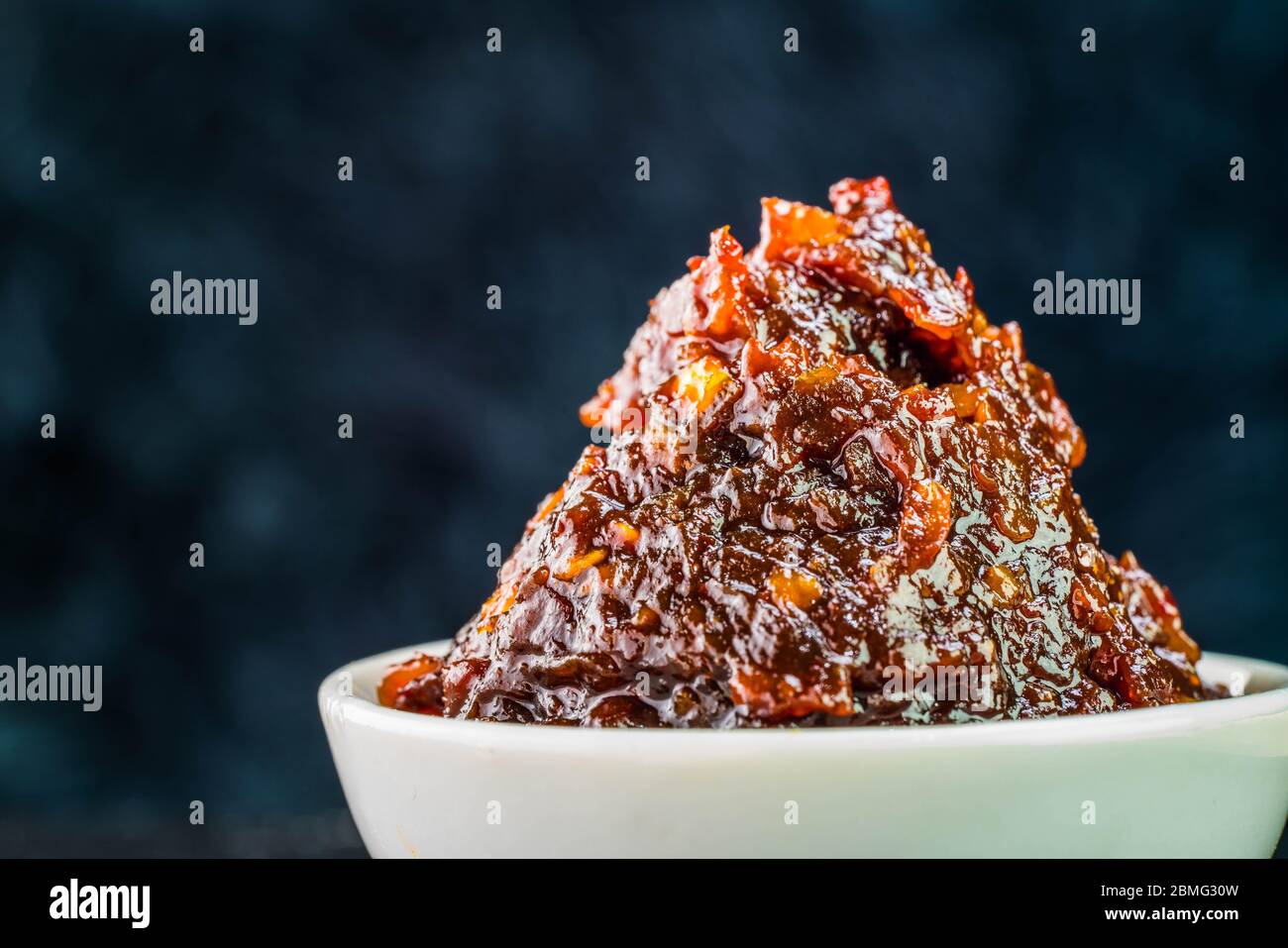 Close up Spicy chili paste in white ceramic container on dark ...