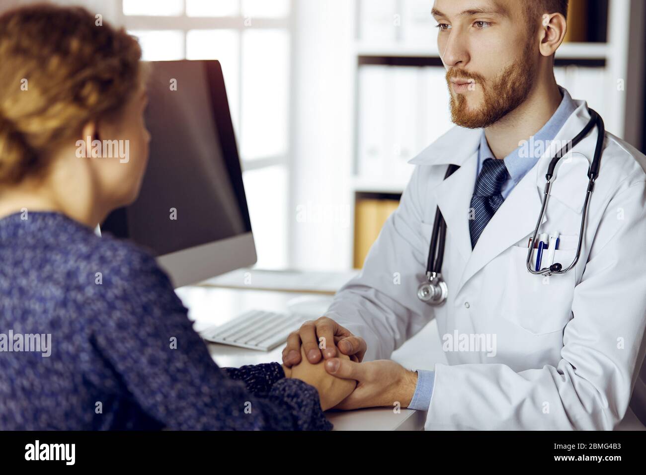 Friendly red-beard doctor reassuring his female patient. Medical ethics ...
