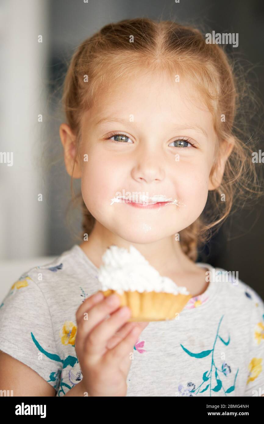 Cheerful smiling child girl eating a delicious cake and showing thumbs ...