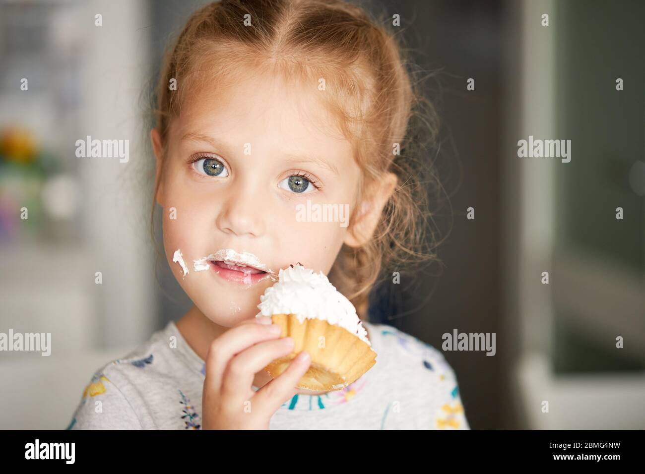 Cheerful smiling child girl eating a delicious cake and showing thumbs ...