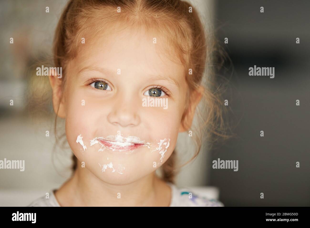 Cheerful smiling child girl eating a delicious cake and showing thumbs ...
