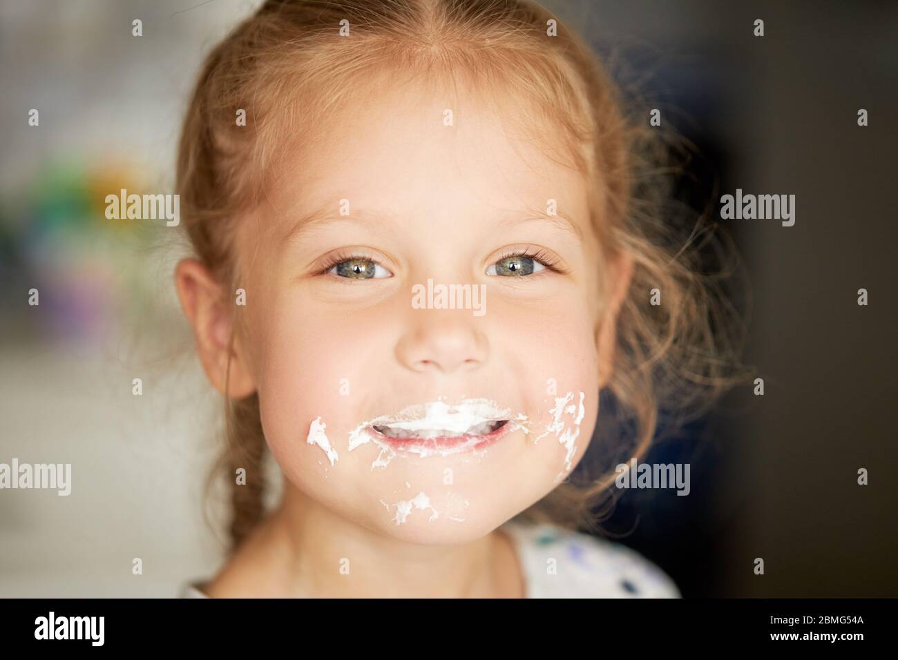 Cheerful smiling child girl eating a delicious cake and showing thumbs ...