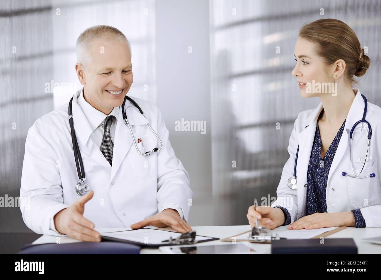 Elderly doctor and his female colleague discussing current disease ...