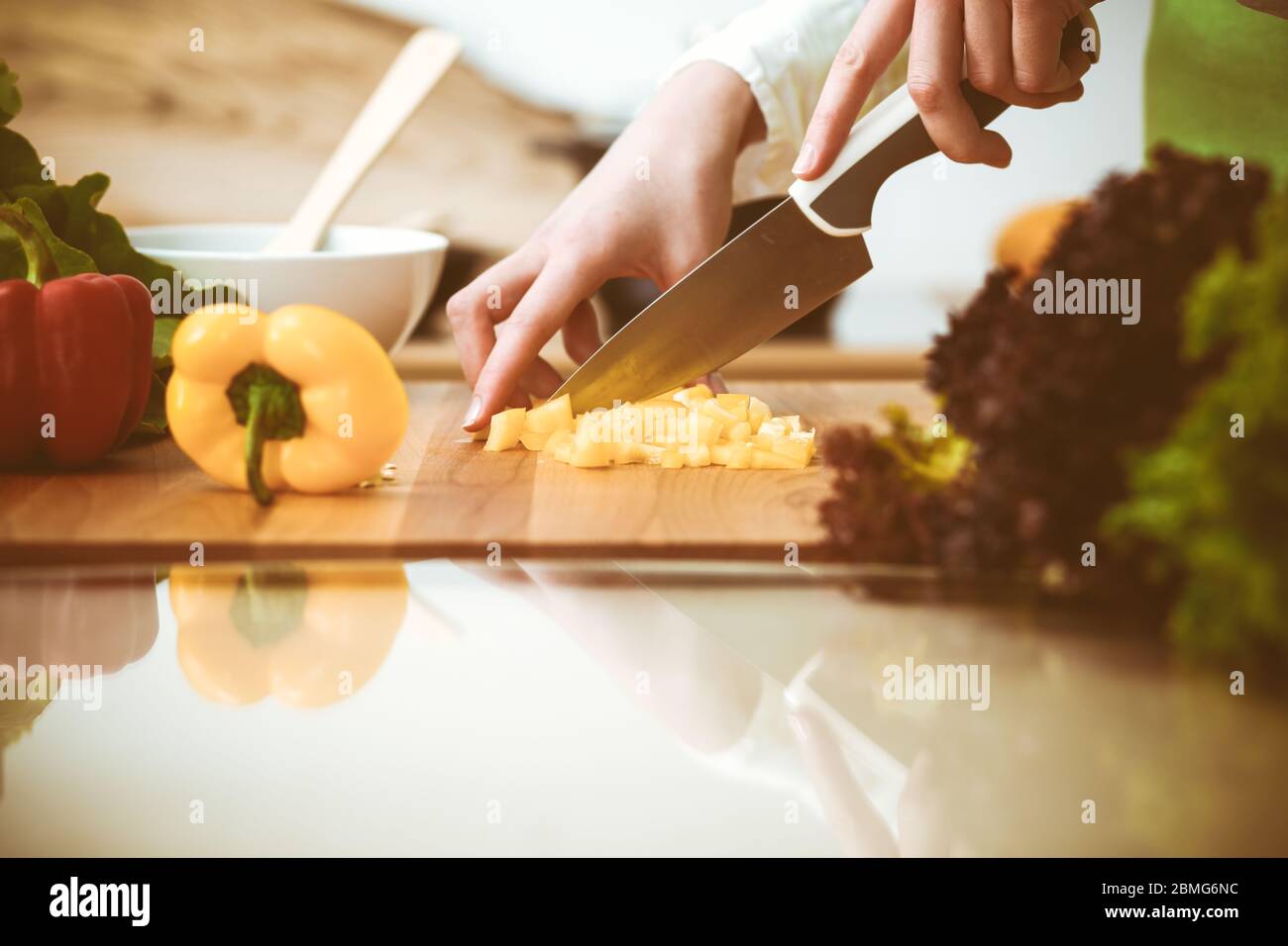 Unknown human hands cooking in kitchen. Woman slicing yellow bell ...