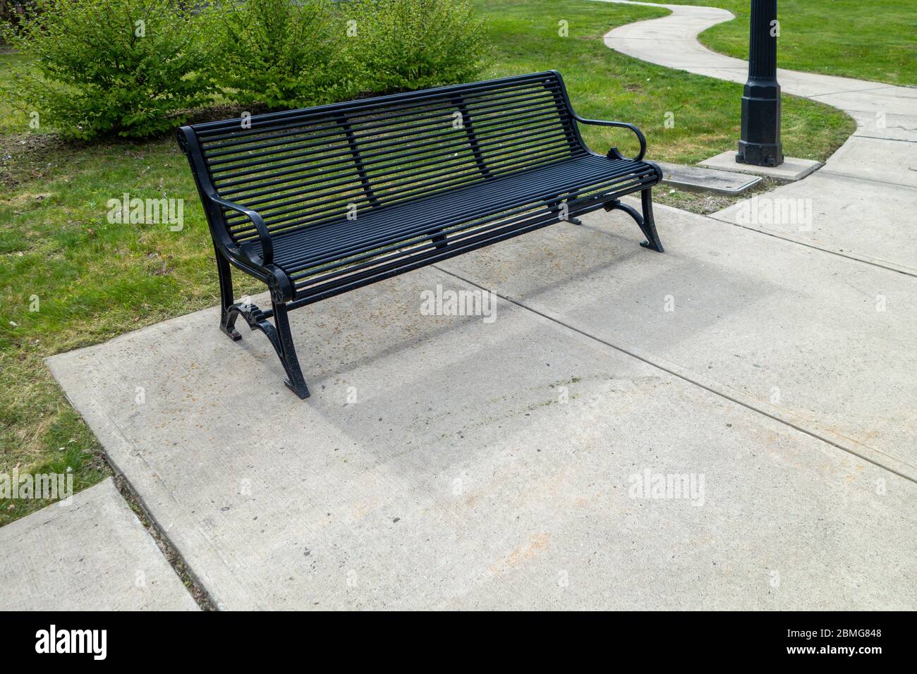 lawn bushes and cement winding sidewalk pathway going into the distance ...