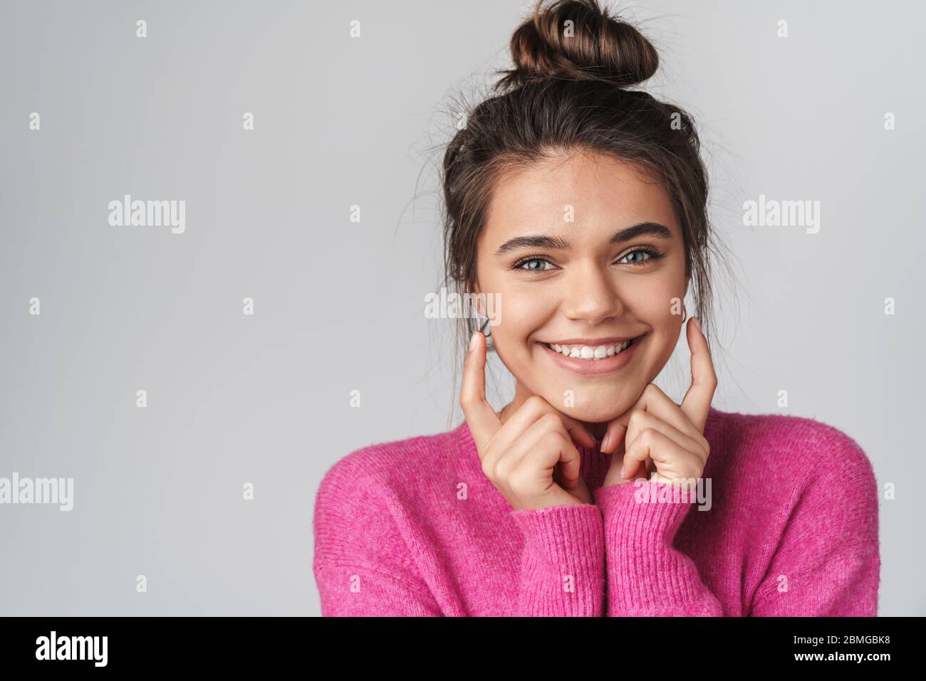 Image of joyful young woman pointing fingers at her cheeks and smiling ...