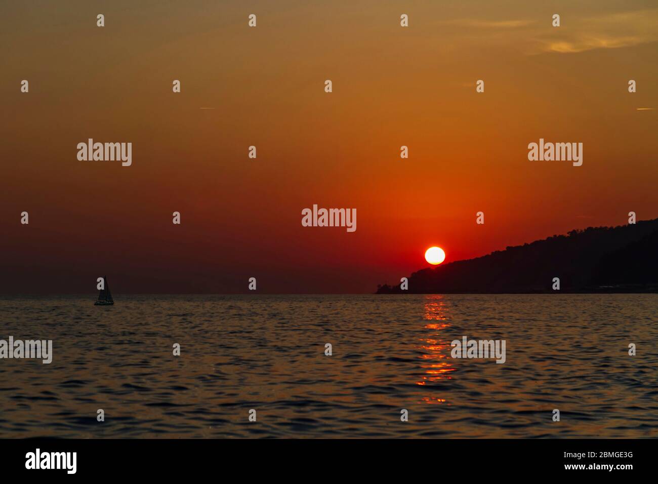 Small sailboat at sea at sunset Stock Photo - Alamy