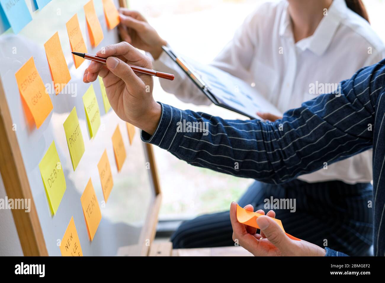 Business people arranging sticky notes commenting and brainstorming on ...