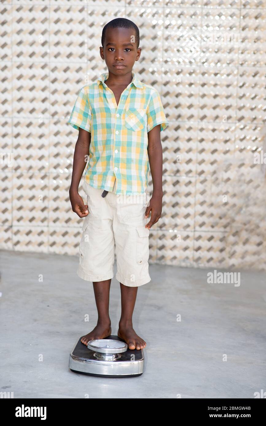 very worried child standing on a scale controls his weight, outdoor ...